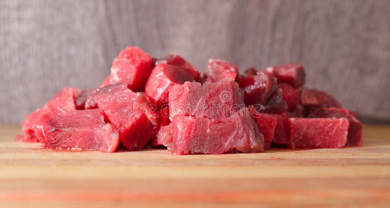 Portion of Red Meat Sliced into Cubes Over a Wooden Board Stock Photo ...
