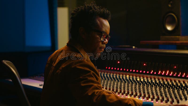 Portrait of African American Audio Technician Uses Mixing Console with ...