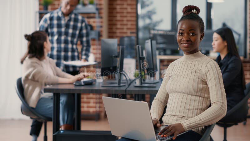 Portrait Of African American Coder Sitting Down Writing Programming Language On Laptop Looking