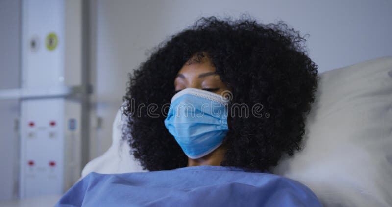 Portrait Of African American Female Patient Wearing Face Mask Lying On