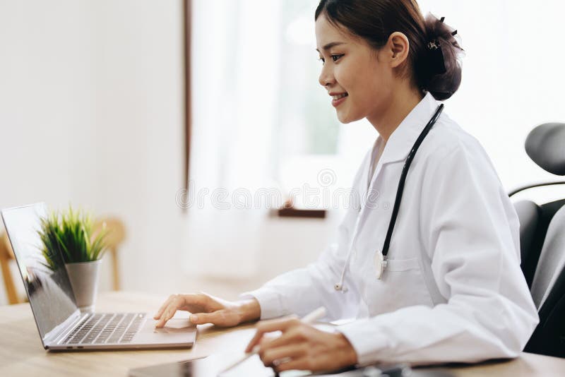 Portrait of an Asian Female Doctor Using a Computer and Tablet To Work ...