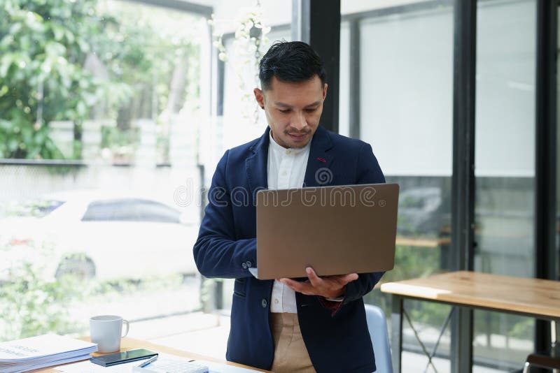 Portrait of an Asian Male Business Owner Standing Using a Computer To ...