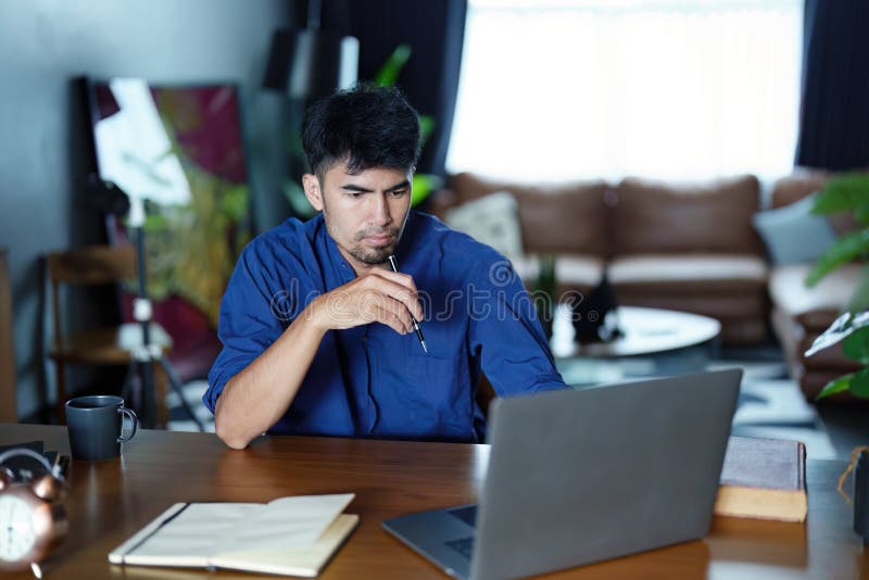 Portrait of an Asian Man Using a Computer and Note Book To Record His ... Portrait of an Asian Man Using a Computer and Note Book To Record His ...