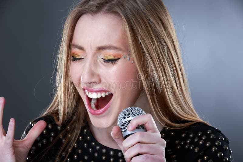 Portrait of a Beautiful Blonde Young Woman Singing into Microphone ...