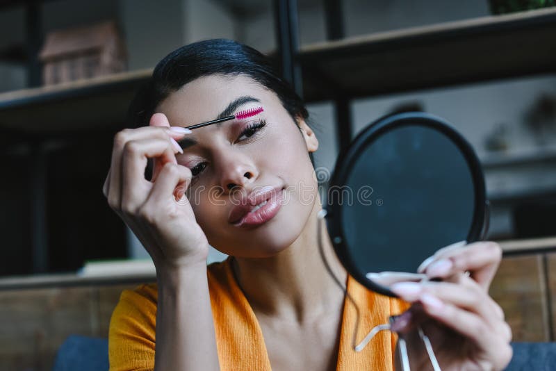 Portrait Of Beautiful Mixed Race Girl In Orange Shirt Applying Mascara