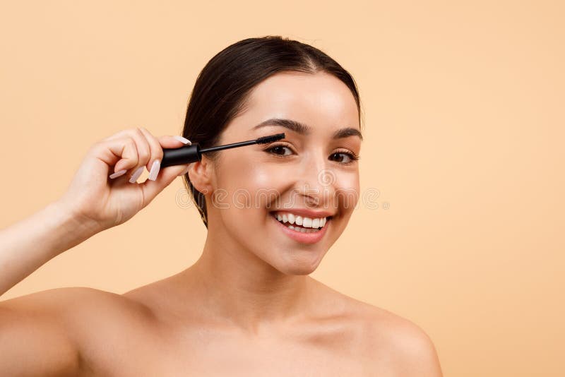 Portrait Of Beautiful Smiling Young Indian Woman Applying Mascara On