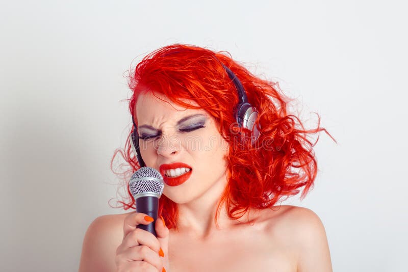 Portrait Of Beautiful Young Woman In Headphones Singing Into A