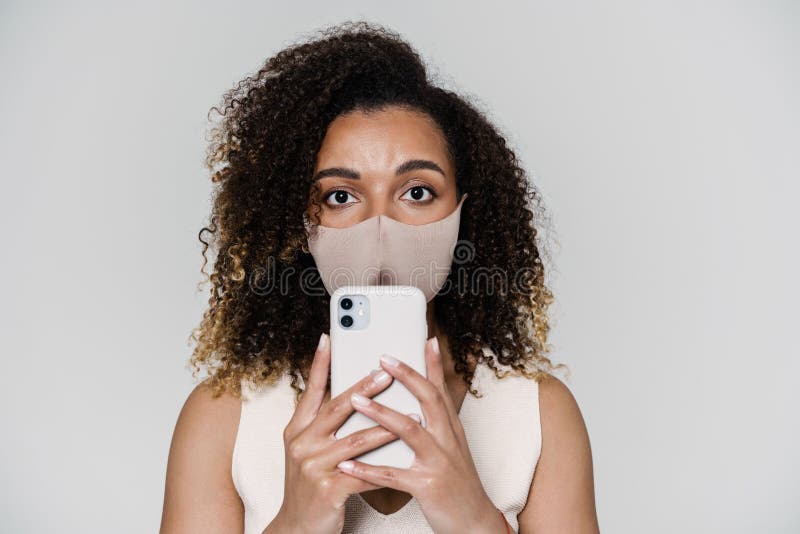 The Portrait of a Black Woman in a Mask Holding a Phone Aiming at the ...