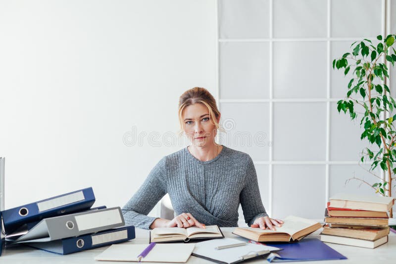 Portrait of a Businesswoman at a Table with Books and Documents at Work ...