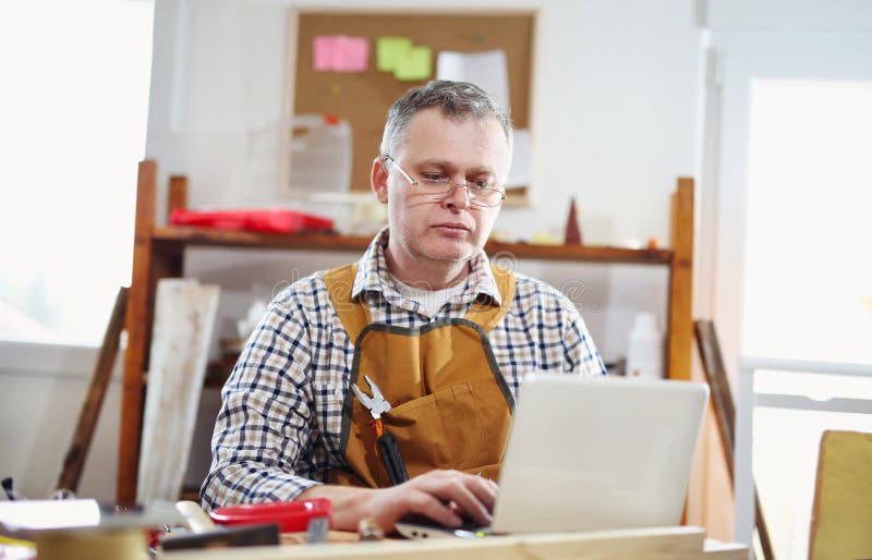 Portrait of Carpenter Sitting at His Workshop and Working with Laptop ...