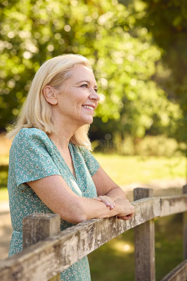 Portrait of Casually Dressed Mature or Senior Woman Leaning on Fence on ... Portrait of Casually Dressed Mature or Senior Woman Leaning on Fence on ...