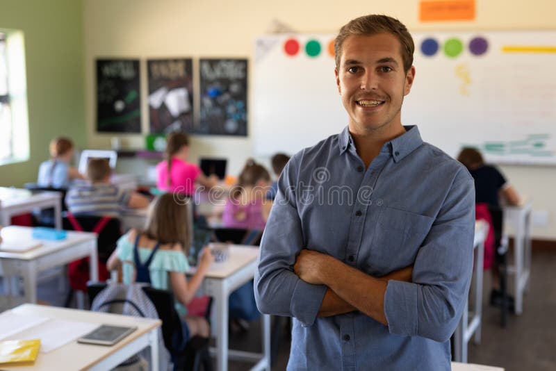 Male School Teacher Standing With Arms Crossed In An Elementary School