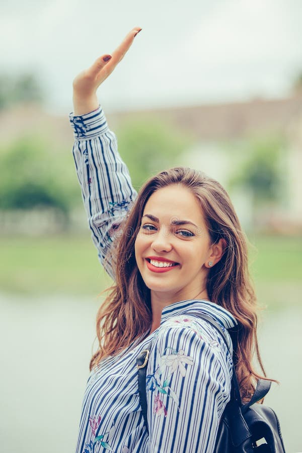 Portrait Of A Cheerful Smiling Girl While Walking Outdoors And Waving