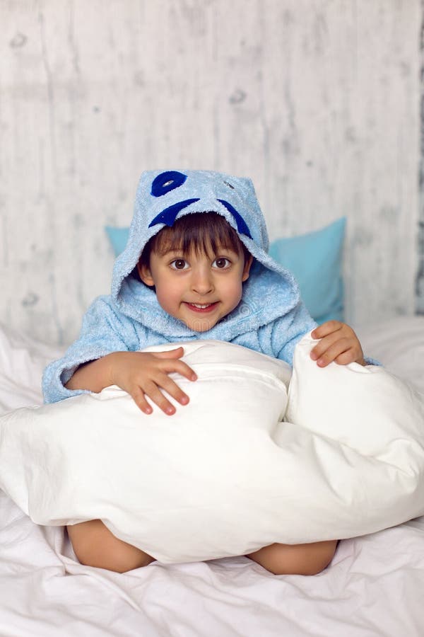 Portrait of a Child in a Blue Robe Sitting on a White Bed Stock Photo ...