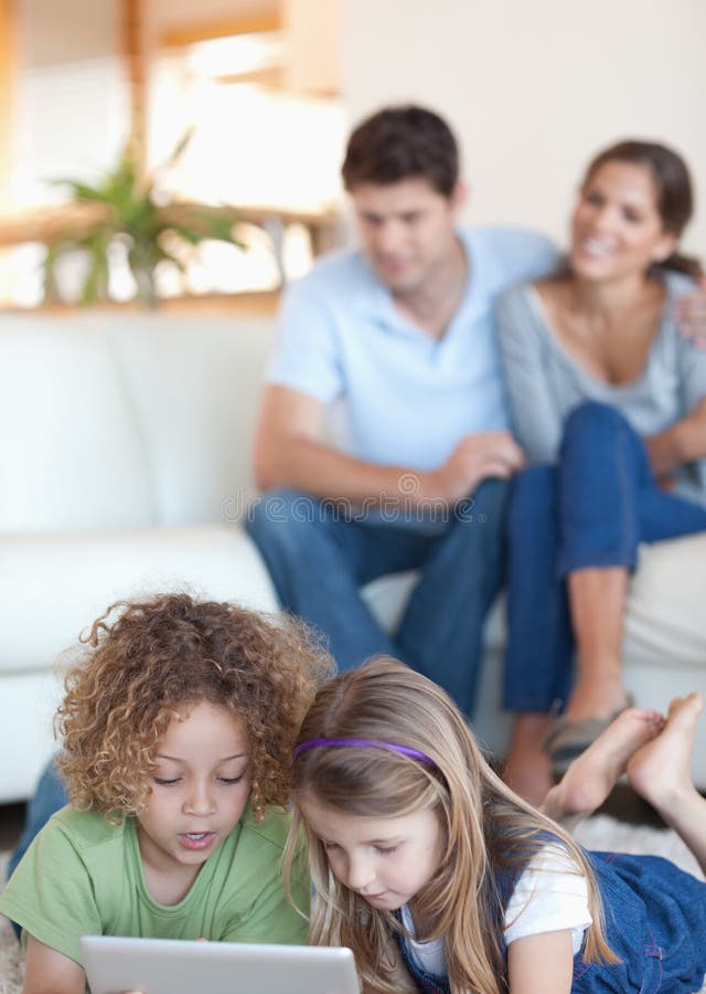 Portrait of Children Using a Tablet Computer while Their Parents Stock ...