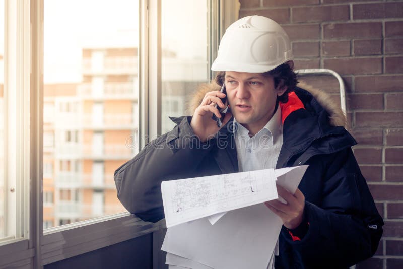 Portrait of Concerned Unshaven Builder Telling by Mobile while Keeping ...
