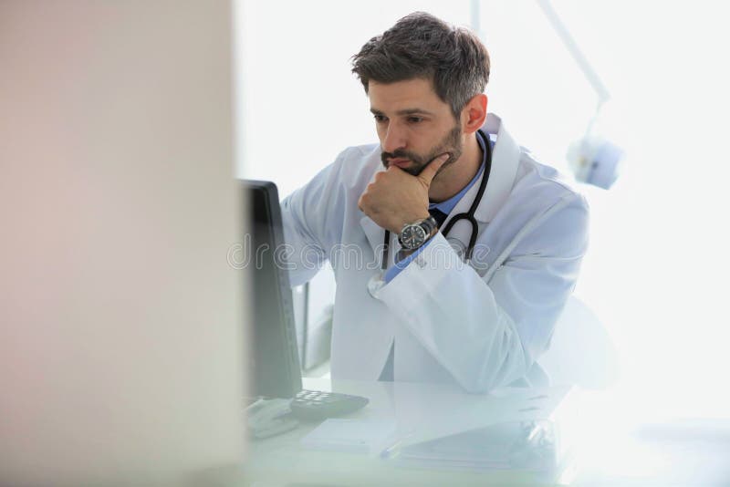 Confident Doctor Using Computer at Desk in Hospital Stock Image - Image ...