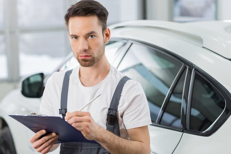 Portrait of Confident Male Maintenance Engineer Writing on Clipboard in ...