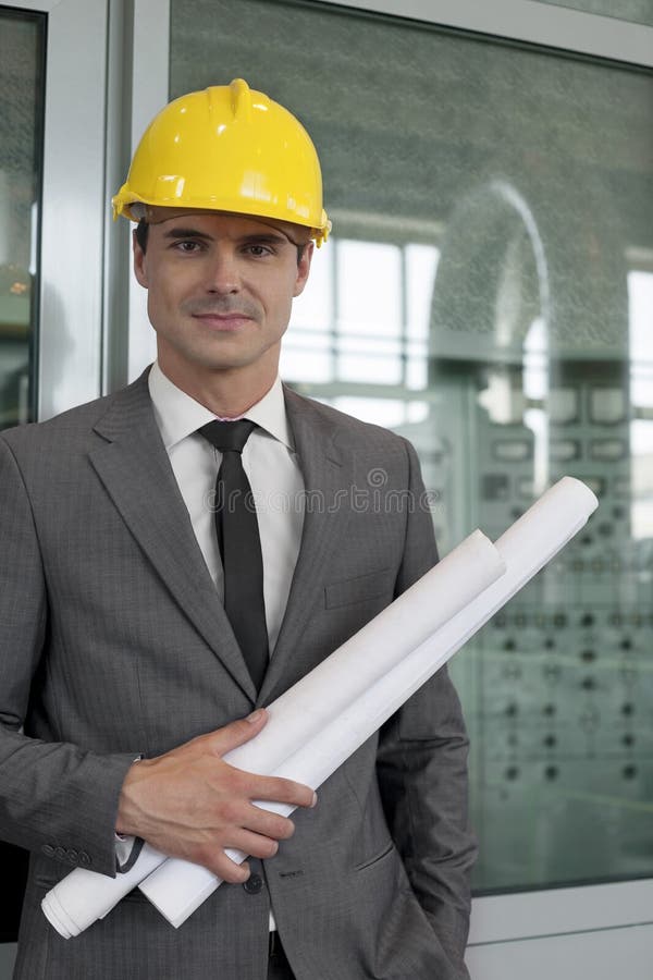 Portrait of Confident Young Male Architect Holding Blueprints in ... Portrait of Confident Young Male Architect Holding Blueprints in ...