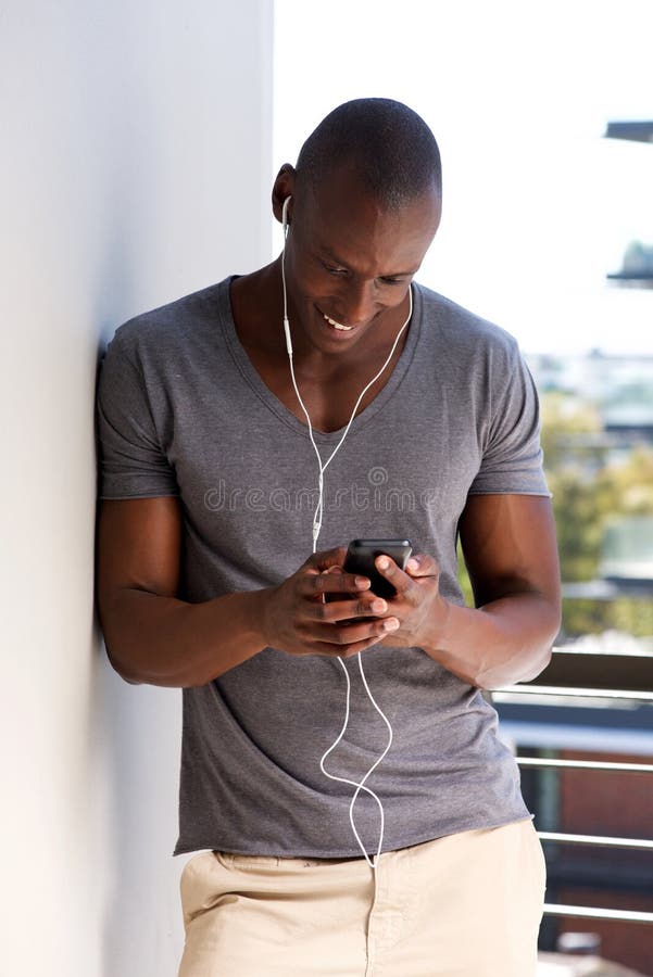 Cool African American Man Leaning Against Wall And Listening To Music