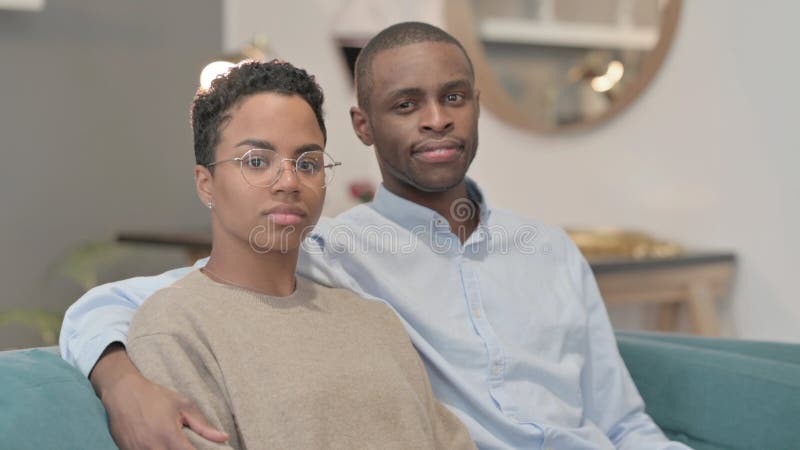 Portrait of Couple Looking at Camera while Sitting on Sofa, Side Pose ...