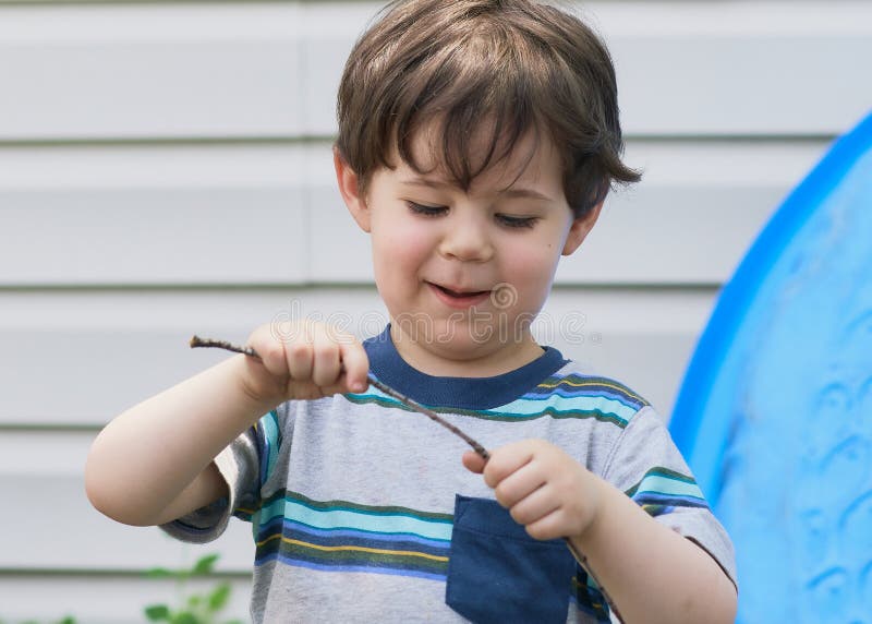 Portrait of a Cute Baby Boy Playing with a Stick in the Backyard Stock ...