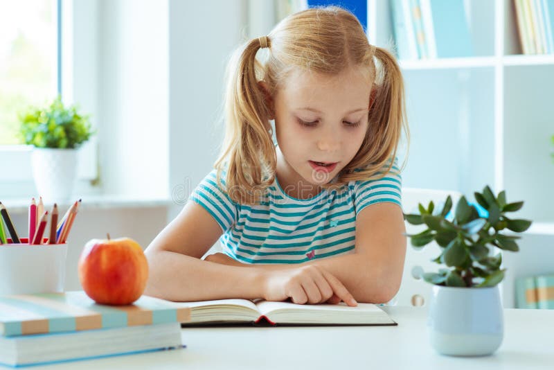 Portrait of a Cute Little Girl Read Book at the Table in Classroom ...