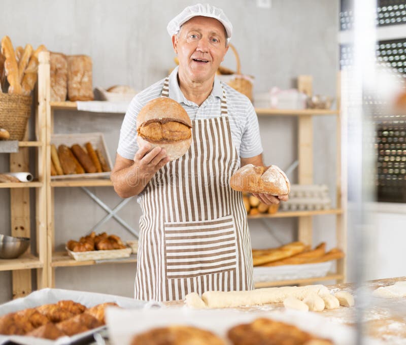 Portrait of Elderly Baker with Bread and Baguettes in Hands in Kitchen ...
