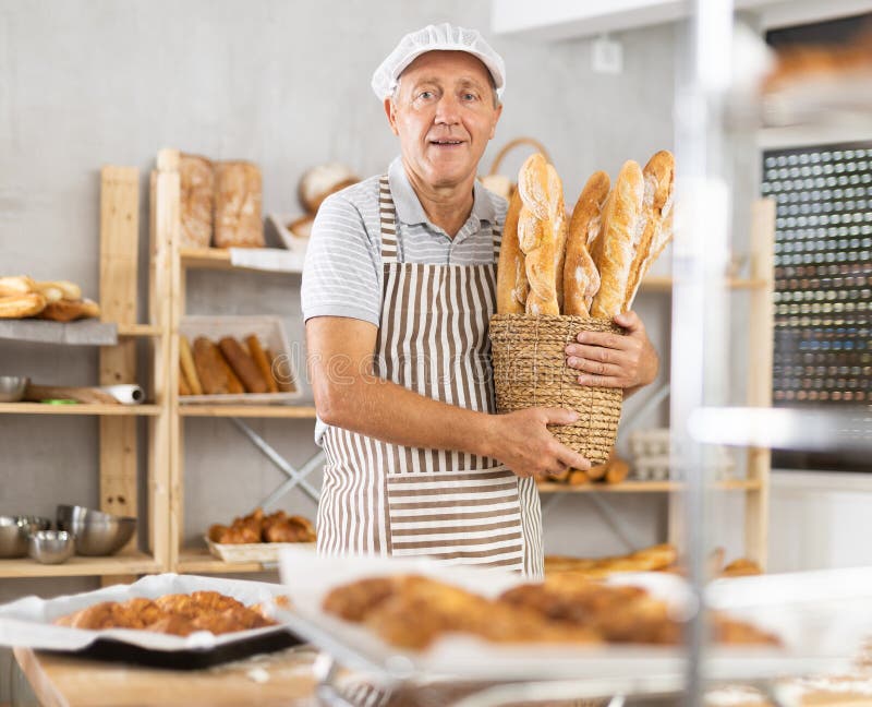 Portrait of Elderly Baker with Bread and Baguettes in Hands in Kitchen ...