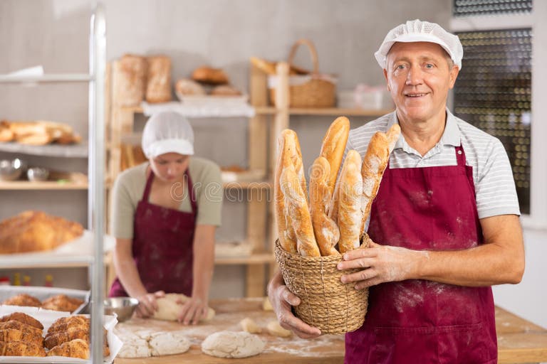 Portrait of Elderly Baker with Bread and Baguettes in Hands in Kitchen ...