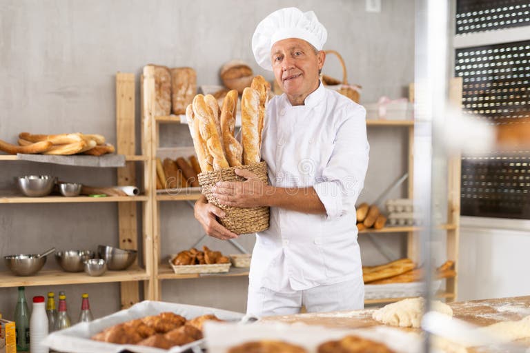 Portrait of Elderly Baker with Bread and Baguettes in Hands in Kitchen ...