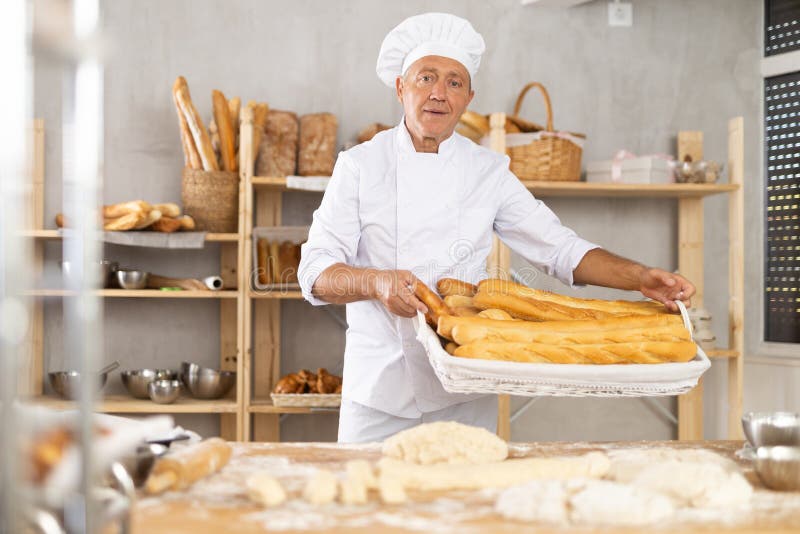 Portrait of Elderly Baker with Bread and Baguettes in Hands in Kitchen ...
