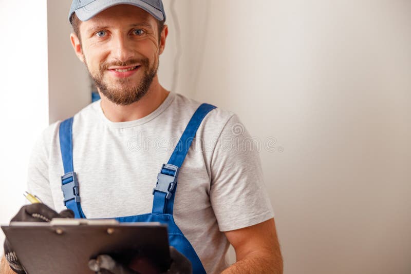 Portrait of Electrical Technician in Uniform Smiling at Camera, Writing ...