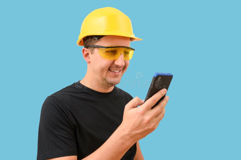 Portrait of an Engineer in a Helmet Using a Phone on a Blue Background ...