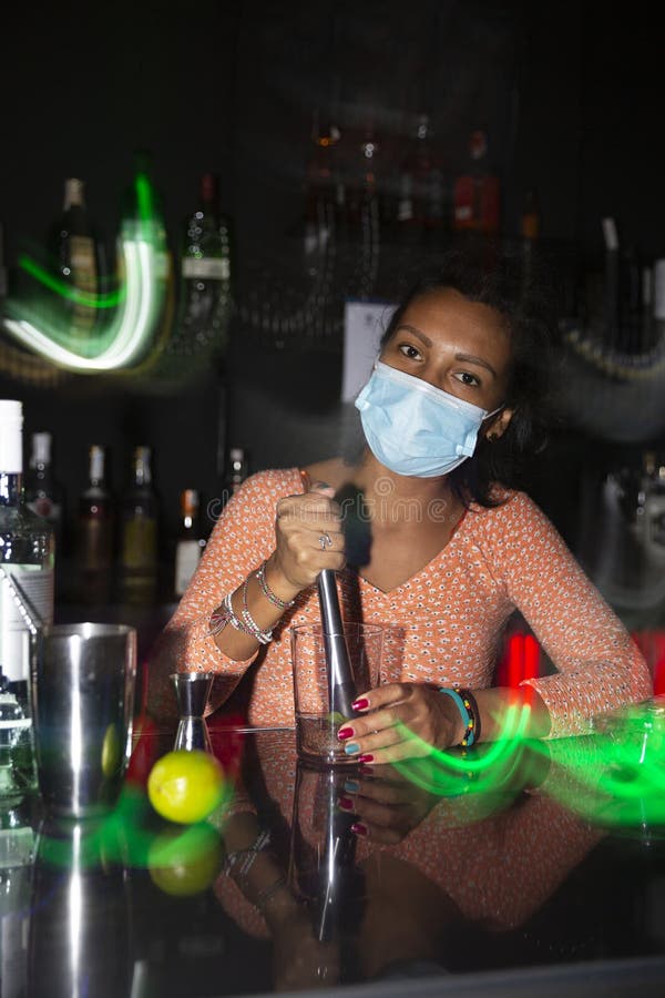 Portrait of an Exotic Waitress with a Face Mask Preparing a Cocktail at ...