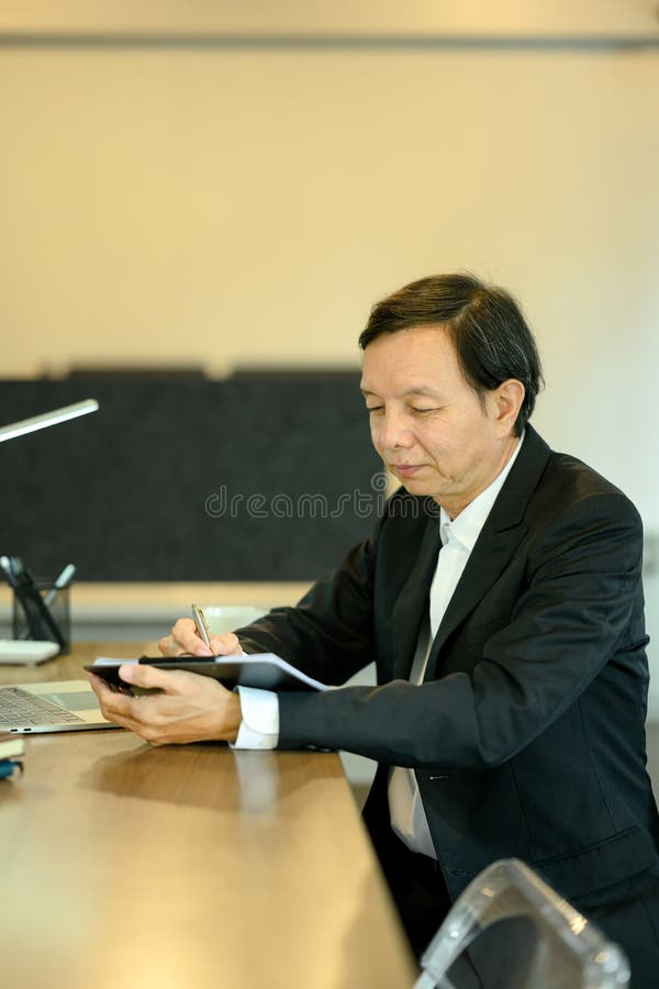 Portrait of Experienced Middle Age Male Manager Reviewing Documents at ...