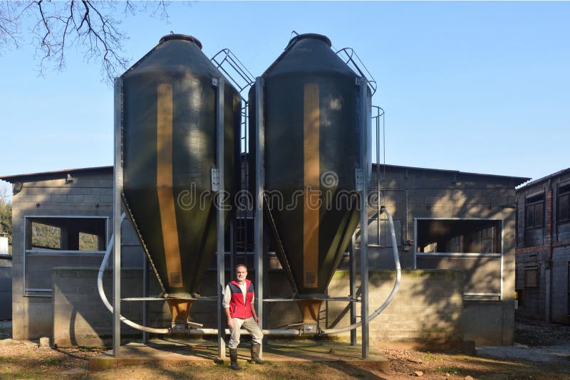 Portrait of a Farmer on the Outside of a Grange with Grain Storege ...