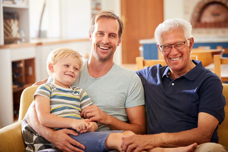 Portrait Of Father With Adult Son And Grandson Relaxing On Sofa And