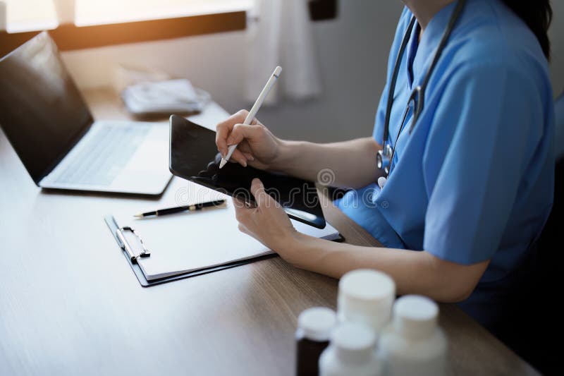 Portrait of a Female Doctor Using a Computer and a Document Analyzing a ...