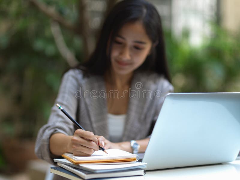 Female Writing on Blank Notebook while Working Laptop on Coffee Table ...