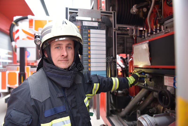 Portrait of a Firefighter at the Emergency Vehicle in the Fire Station ...