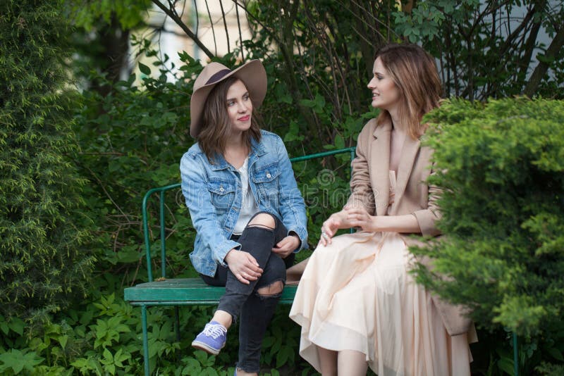 Portrait of Friends Talking and Sitting on a Park Bench Outdoors Stock ...