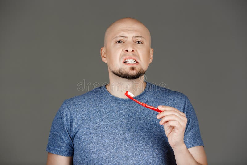 Portrait of Funny Handsome Middle-aged Man in Grey Shirt Brushing Teeth ... Portrait of Funny Handsome Middle-aged Man in Grey Shirt Brushing Teeth ...