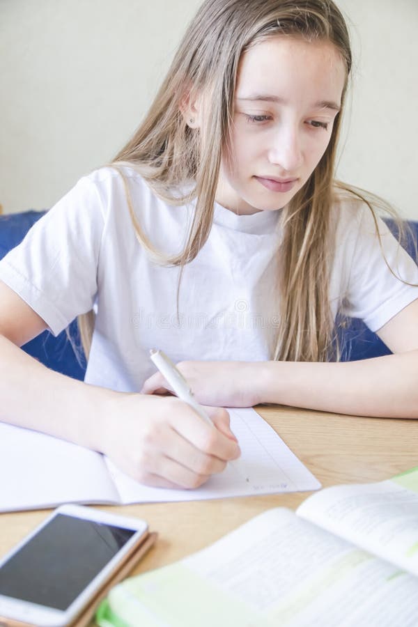 Portrait of Girl in White T-shirt is Sitting and Doing Homework Stock ...