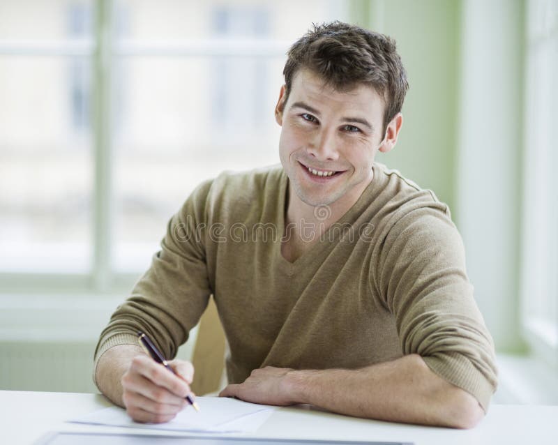 Portrait of Handsome Businessman Writing on Document at Desk in Office ...