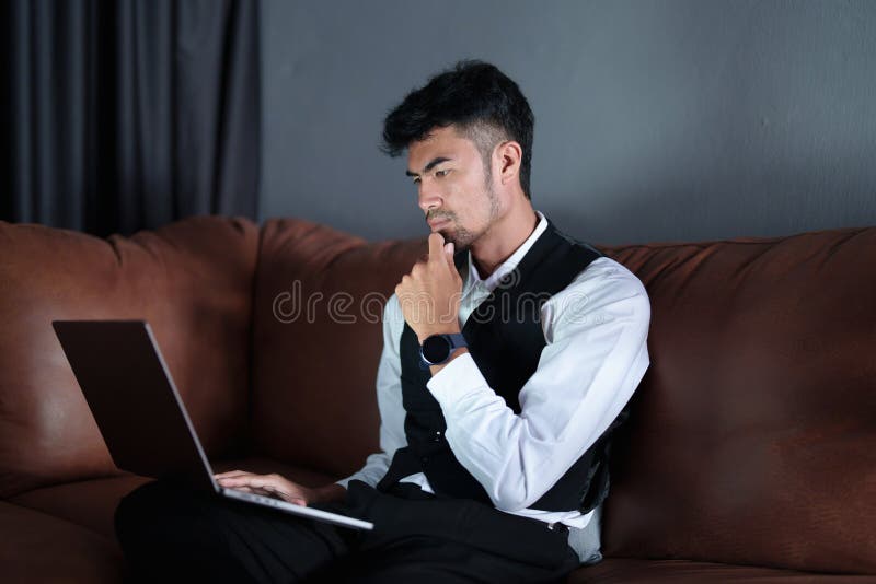 Portrait of a Handsome, Discreet Asian Man Sitting on the Sofa Using a ...