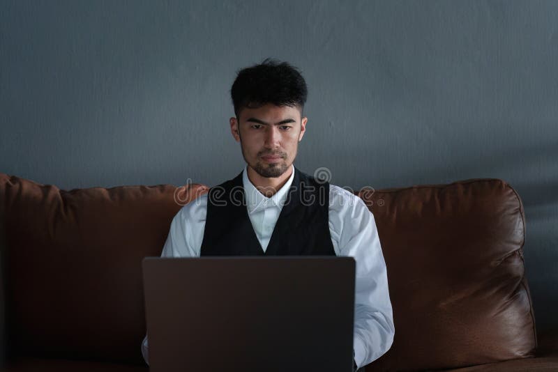 Portrait of a Handsome, Discreet Asian Man Sitting on the Sofa Using a ...