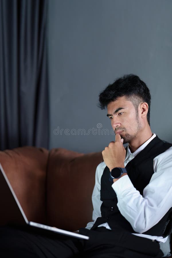 Portrait of a Handsome, Discreet Asian Man Sitting on the Sofa Using a ...
