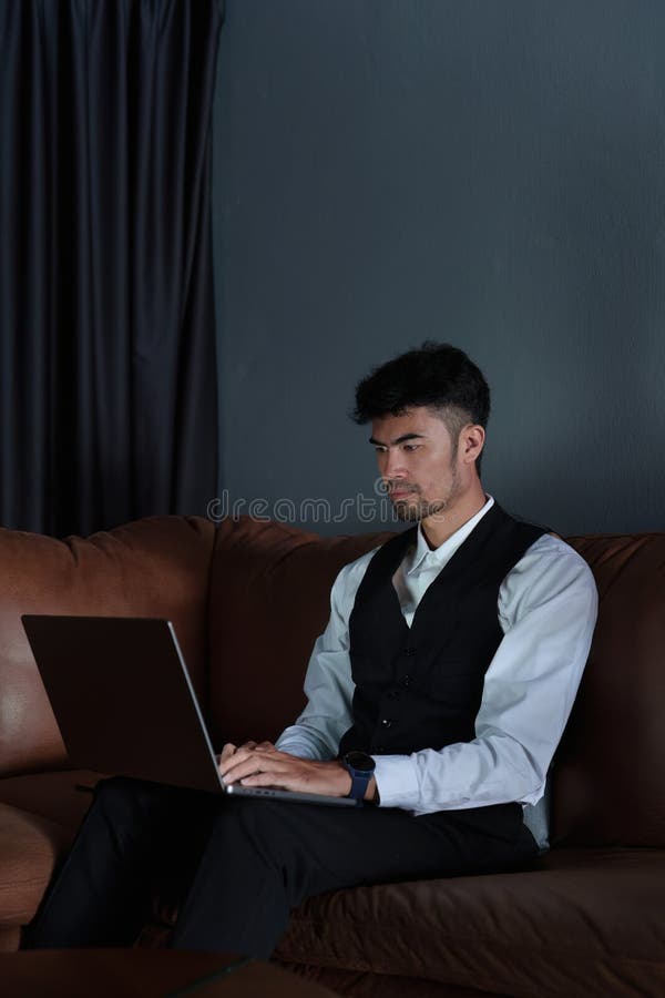 Portrait of a Handsome, Discreet Asian Man Sitting on the Sofa Using a ...