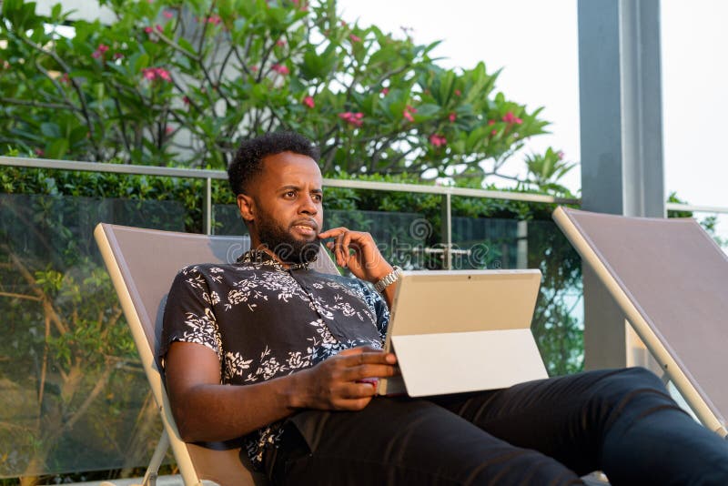 African Man Relaxing Outdoors while Using Laptop Computer and Mobile ...